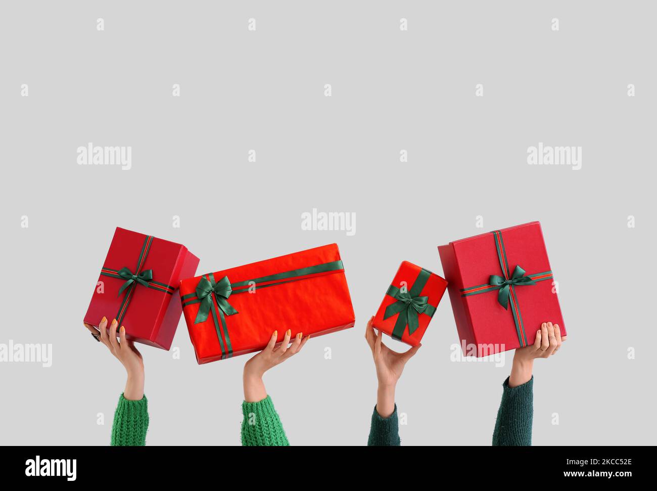 Women with beautiful Christmas gift boxes on grey background Stock ...