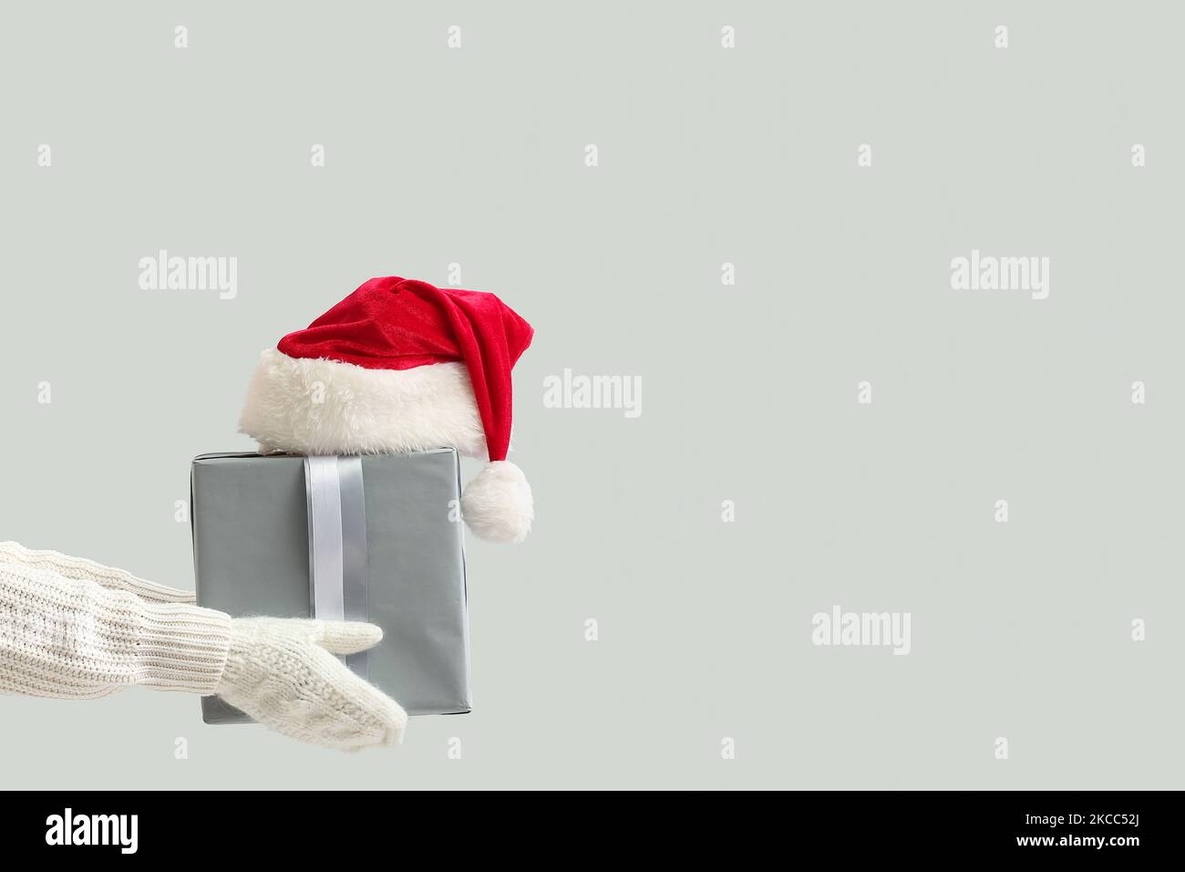 Woman with Christmas gift box and Santa hat on grey background Stock ...