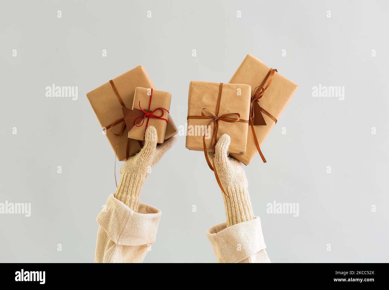 Woman with Christmas gift boxes on grey background Stock Photo - Alamy