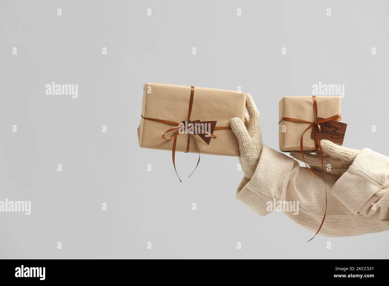 Woman with Christmas gift boxes on grey background Stock Photo - Alamy