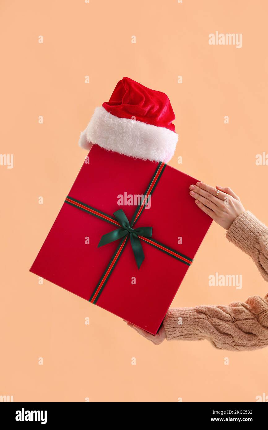 Woman with Christmas gift box and Santa hat on beige background Stock ...