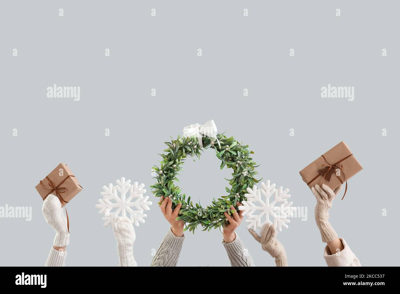 People with gift boxes, snowflakes and Christmas wreath on grey ...