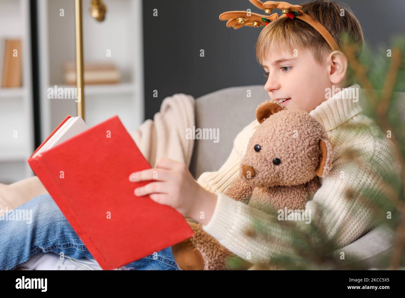 Little boy with toy reading story at home on Christmas eve Stock Photo ...