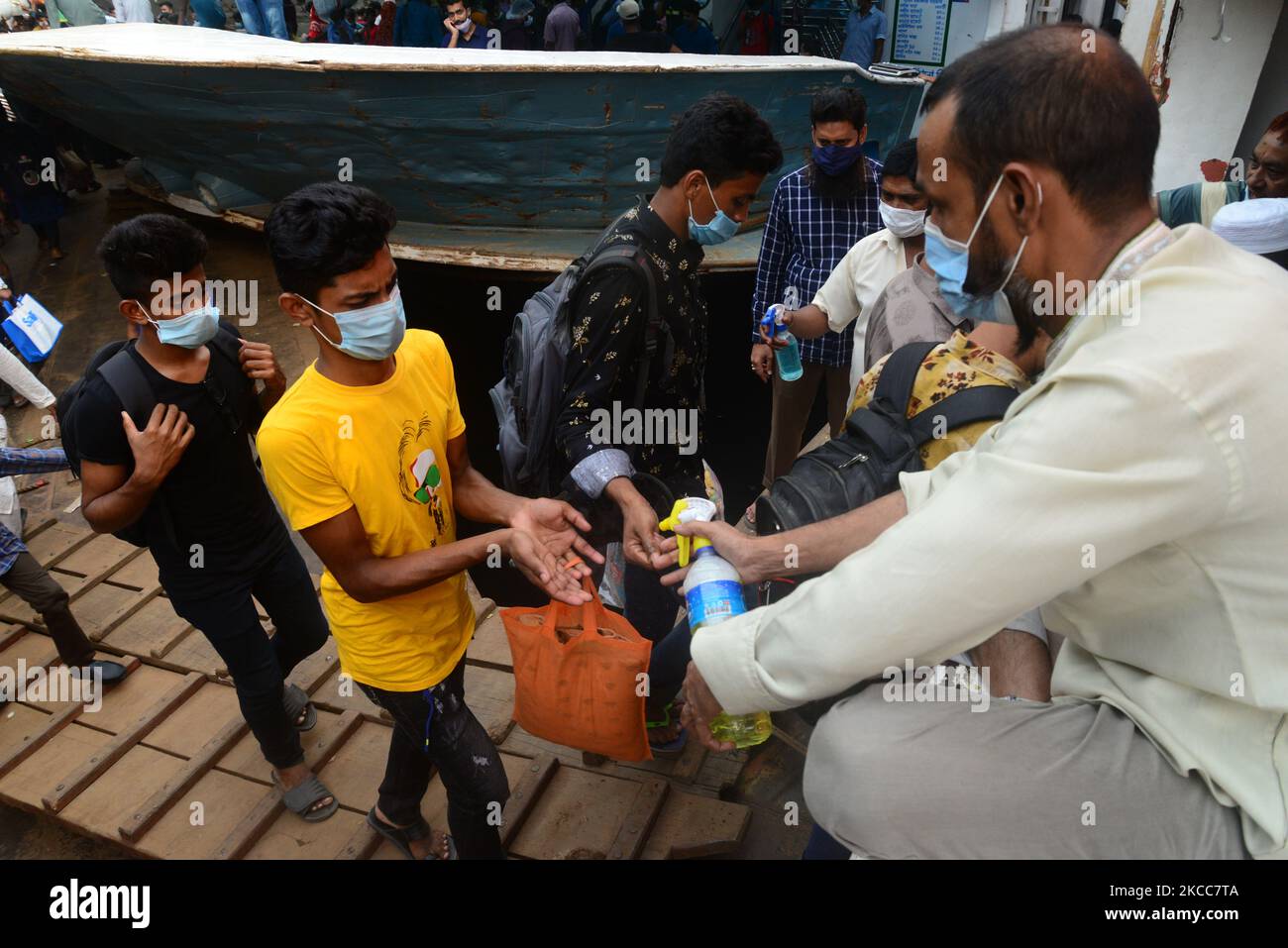 A ferry staff sprays hand sanitizers on passengers hand during onto a ...