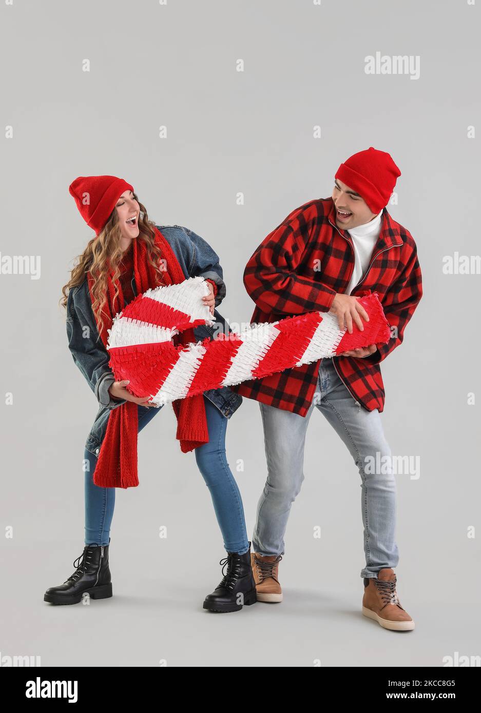 Young couple in love with candy cane pinata on grey background Stock ...