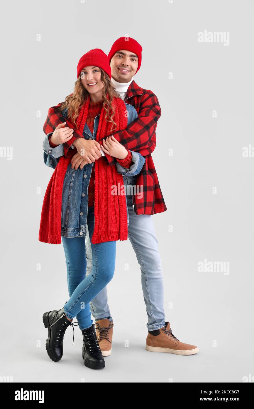 Loving couple in warm clothes hugging on grey background Stock Photo ...
