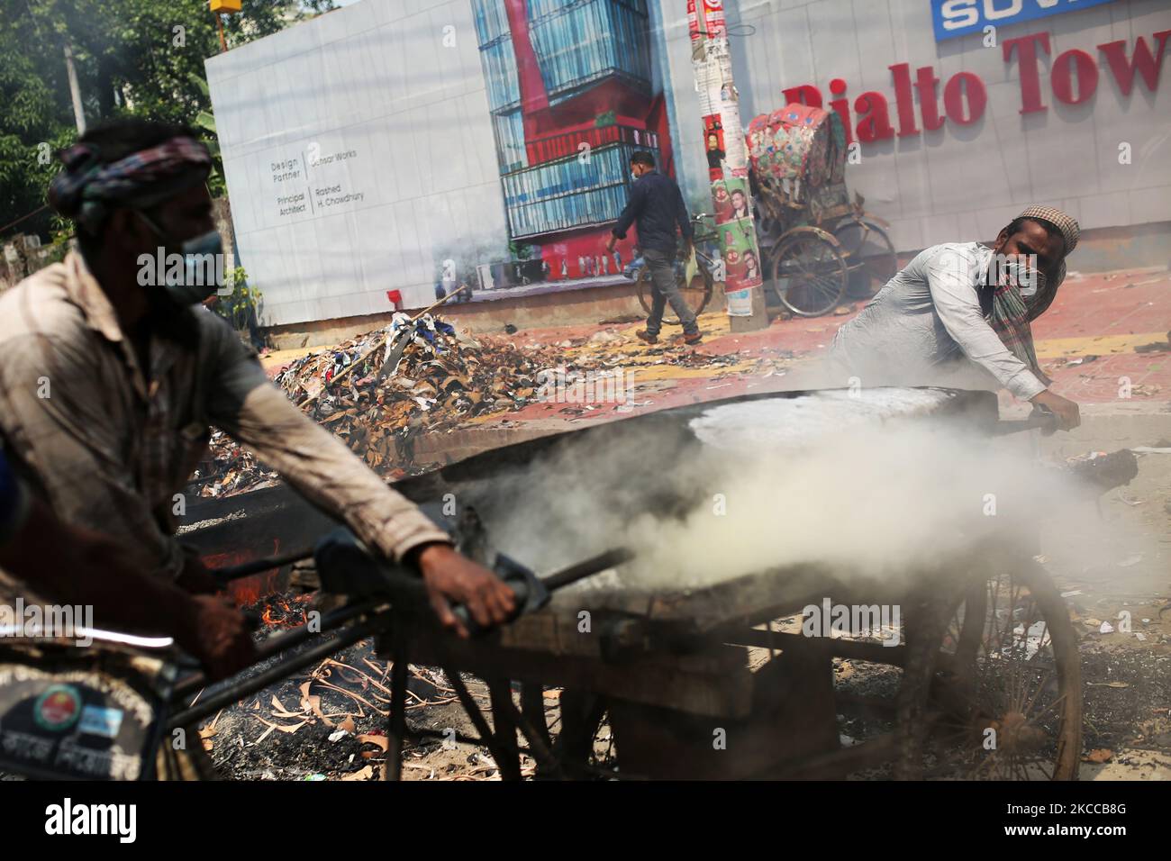 Construction workers working on a road that creates toxic smoke as they ...