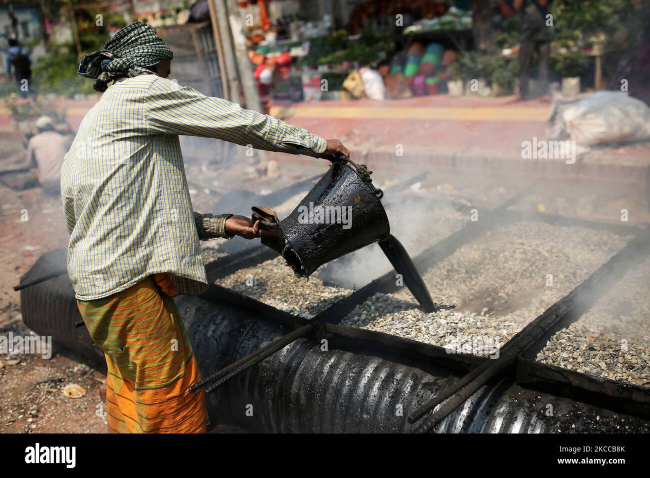 Construction workers working on a road that creates toxic smoke as they ...