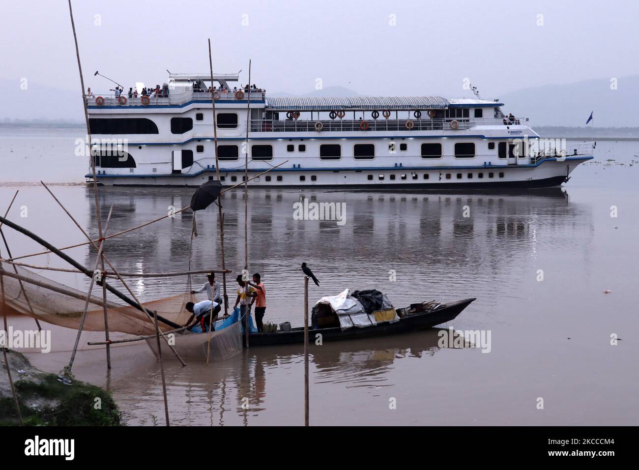 A luxury boat moving as fisherman fishing in the Brahmaputra river, in ...