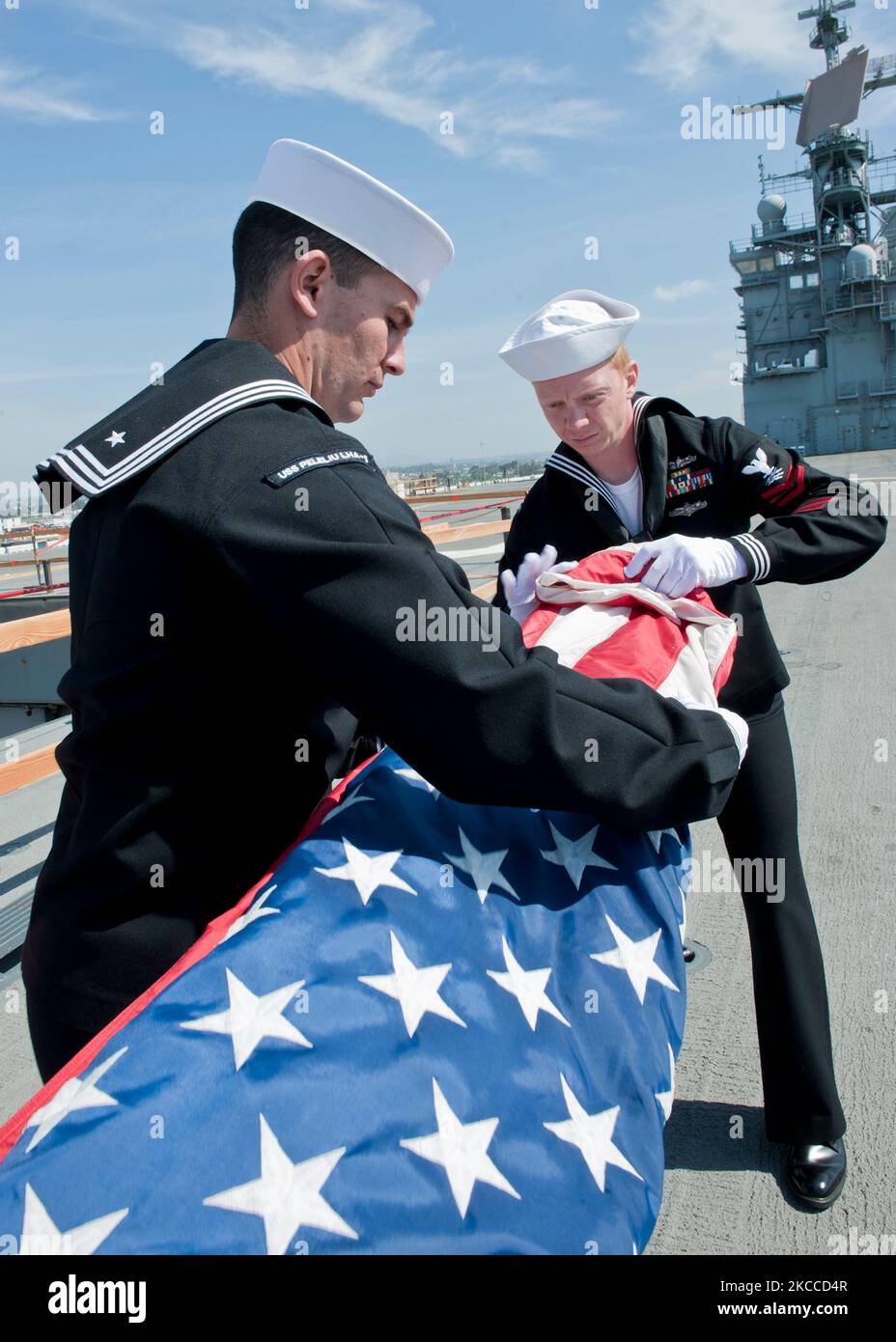 Sailors lower and prepare the ship's colors during a decommissioning ...