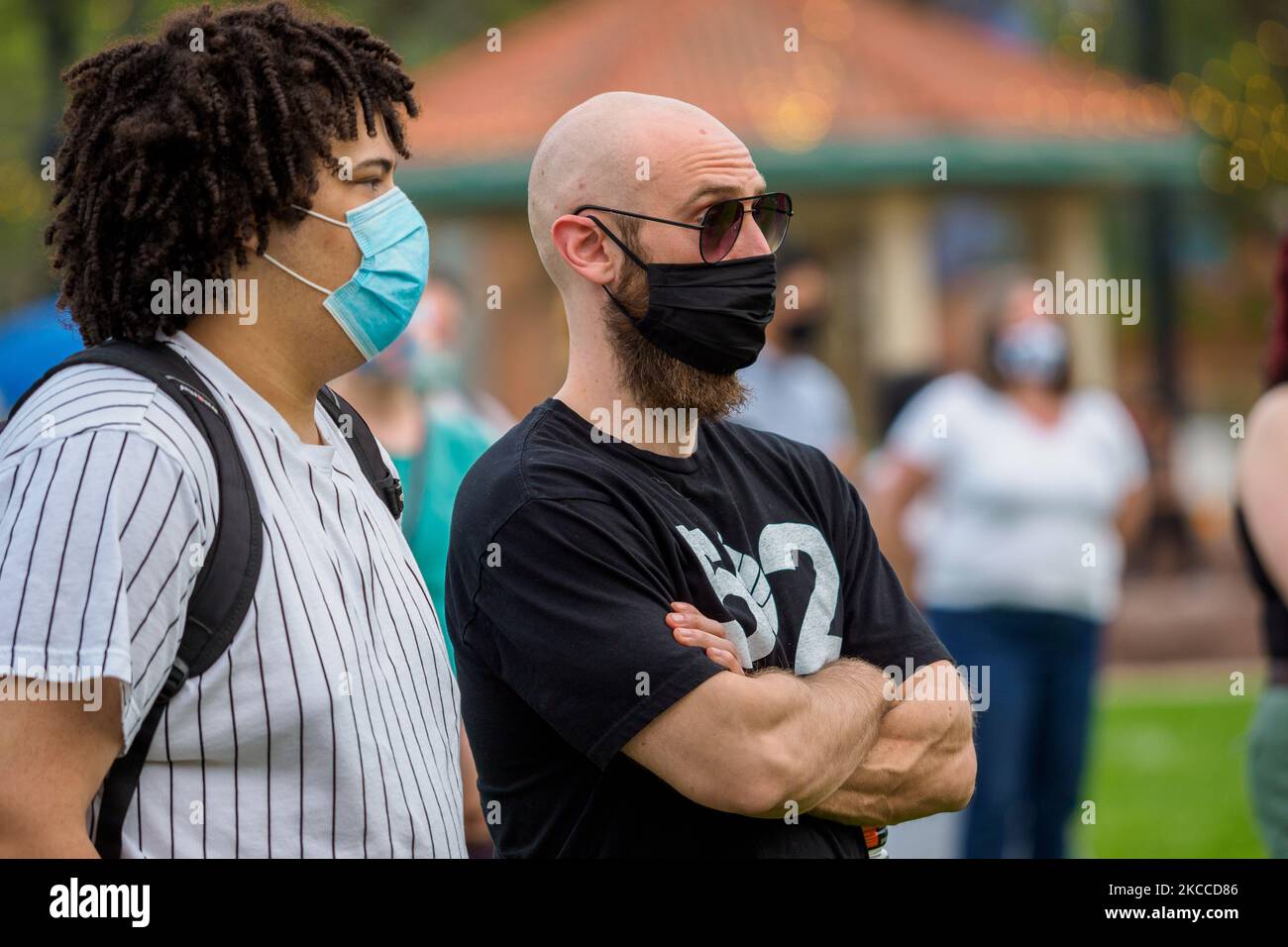 People listen to an organizer address the crowd as people gather at ...