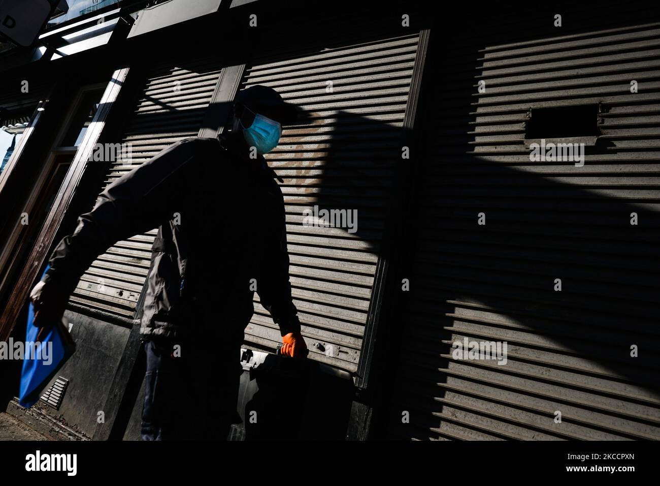 A man wearing a face mask walks past a closed business premises in ...