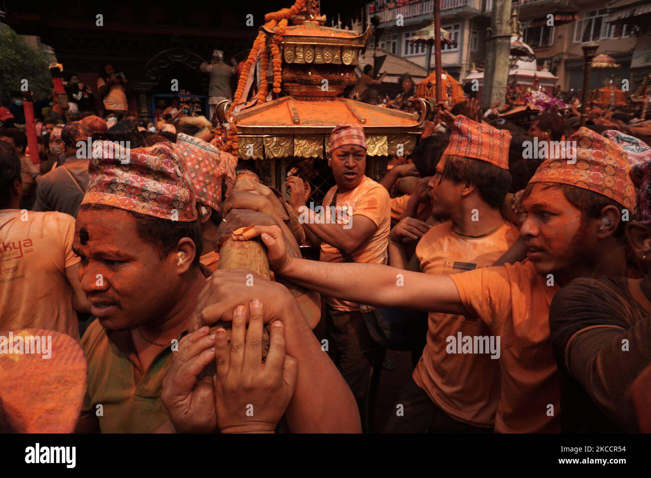 People covered in vermilion powder carry chariots as they circle the ...
