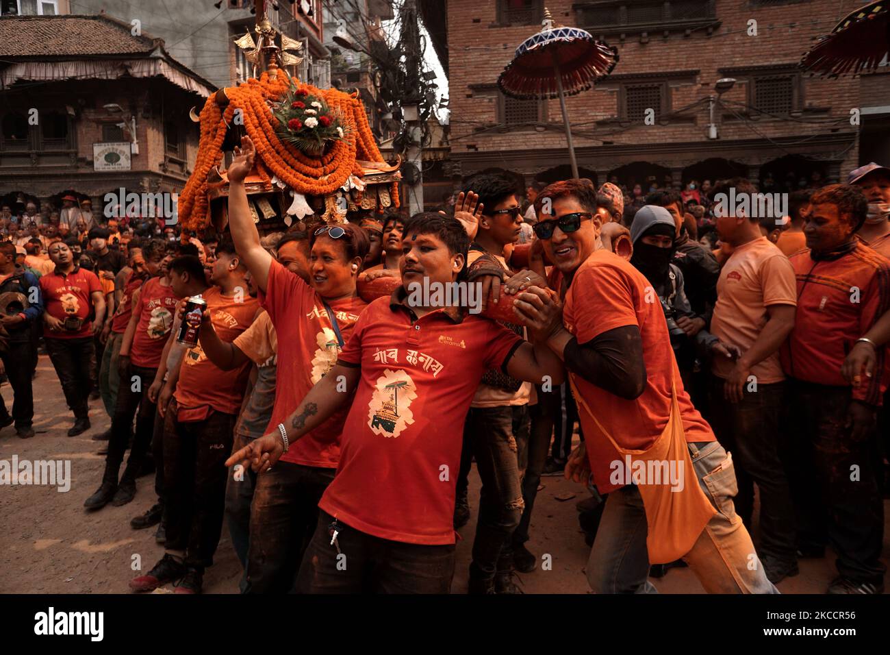 People covered in vermilion powder carry chariots as they circle the ...