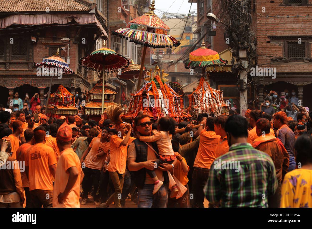 People covered in vermilion powder carry chariots as they circle the ...