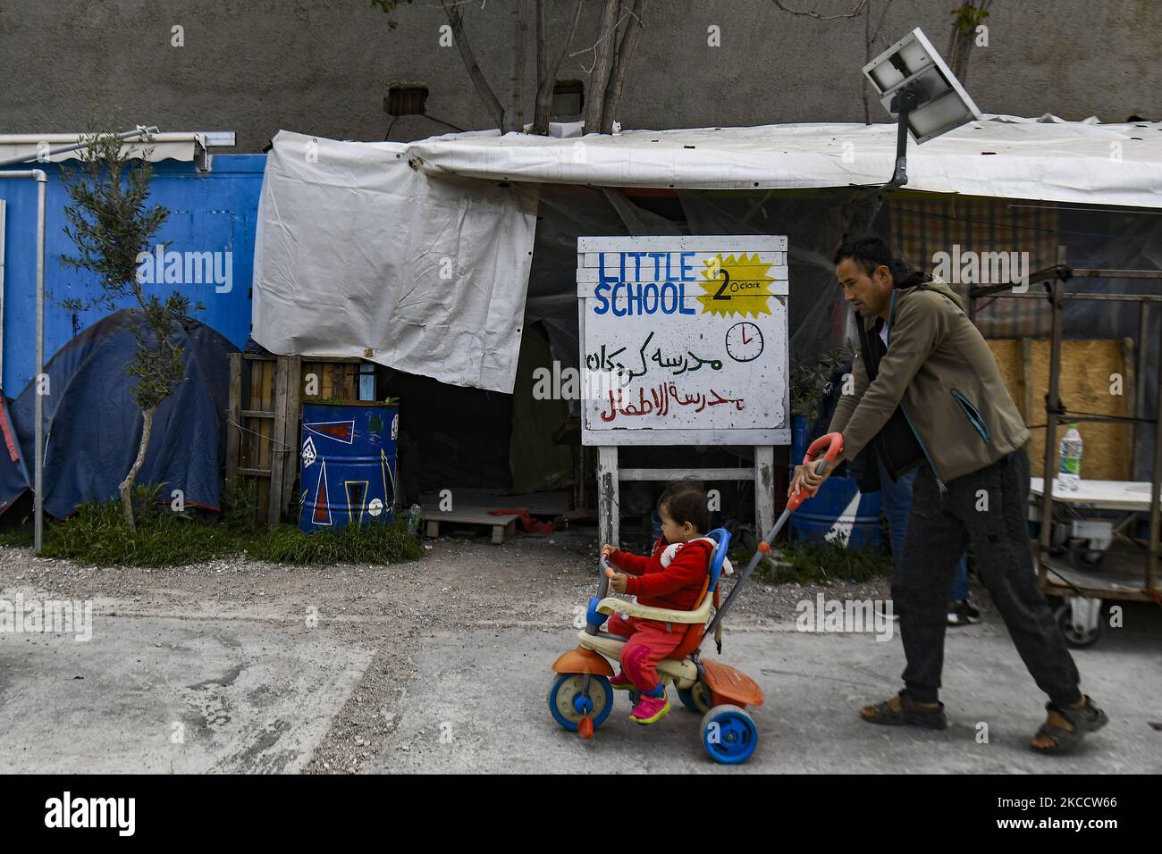 A father walks with his child outside a scholl at Eleonas refugee camp ...