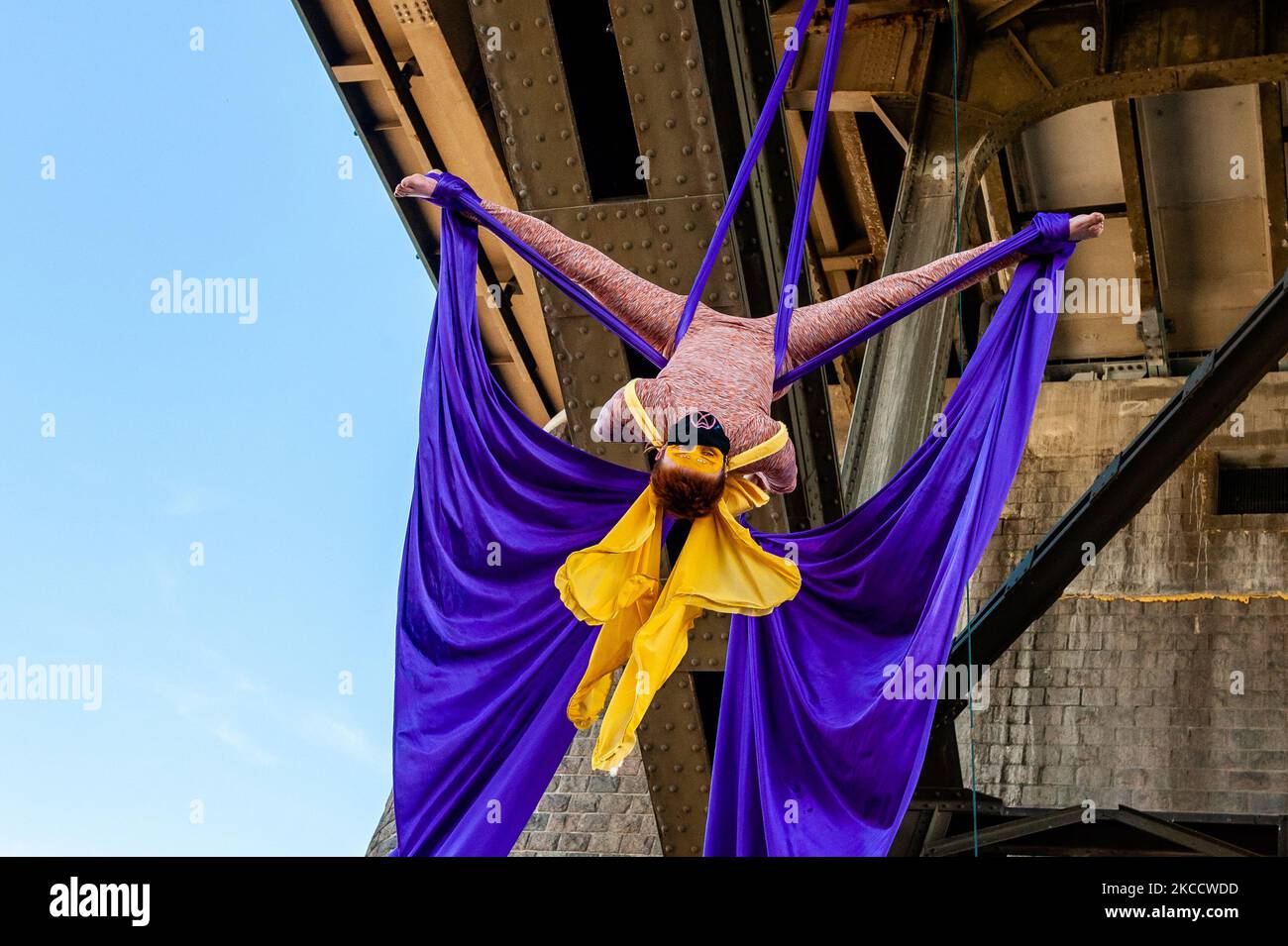 An acrobat is performing with aerial silk while an XR banner is hanging ...