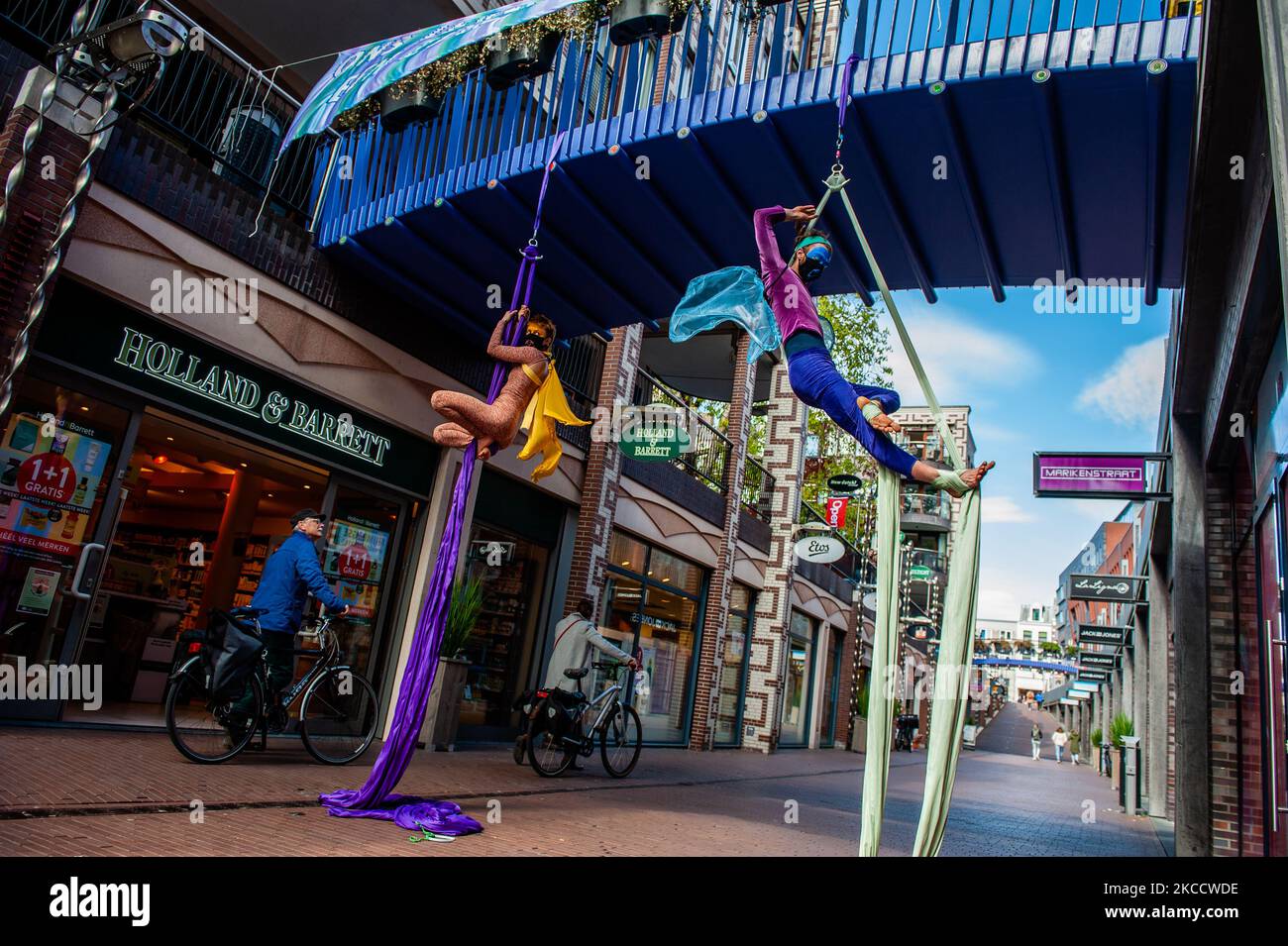 Two aerial acrobats are performing with aerial silk in the middle of ...