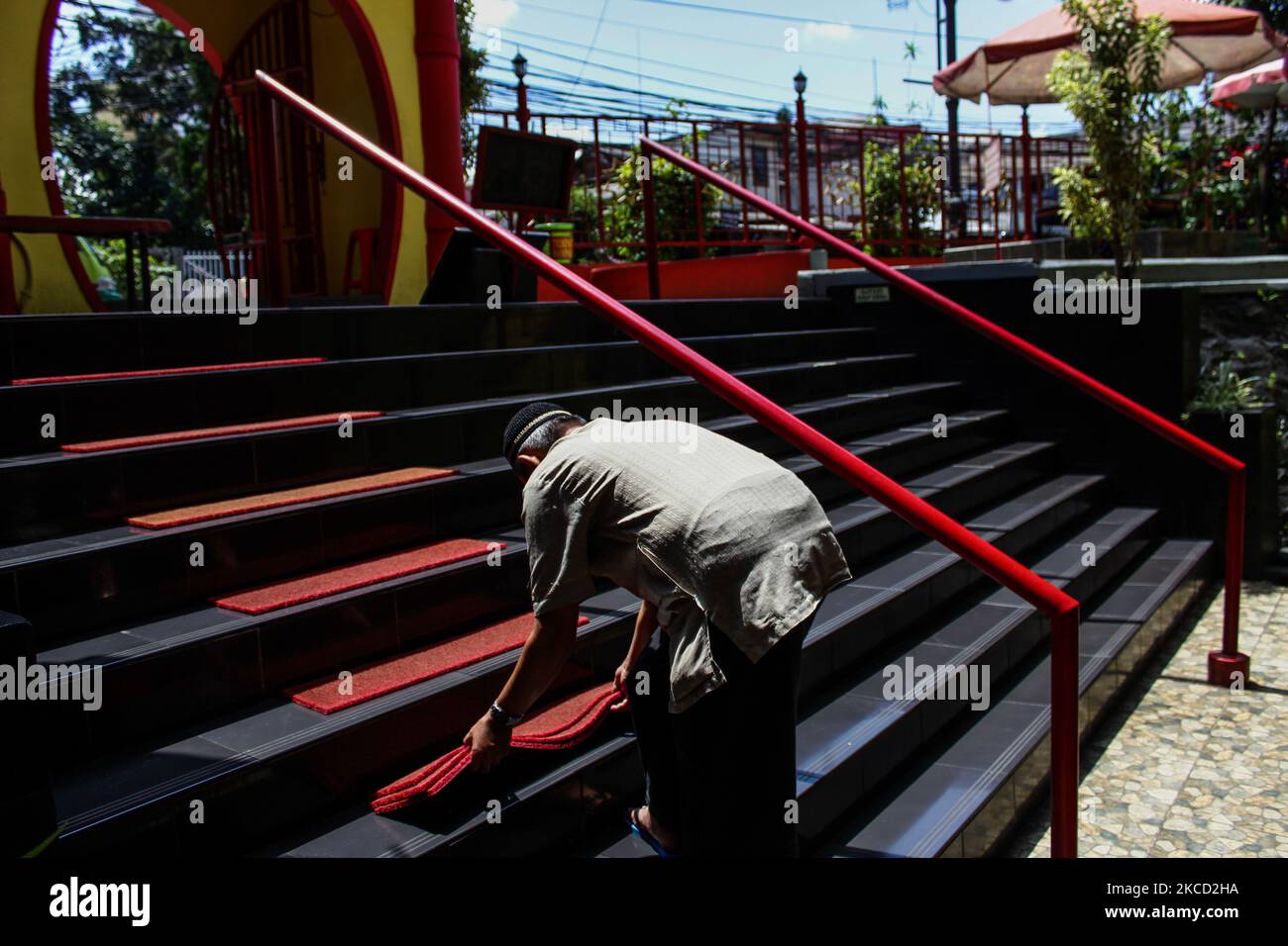 A mosque staff member prepares a carpet at the entrance Al Imtizaj ...