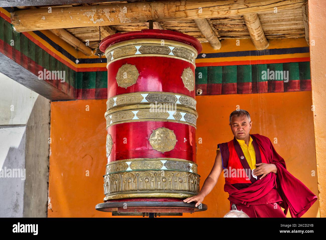 Buddhist monk turns a large prayer wheel at the Lamayuru Monastery ...