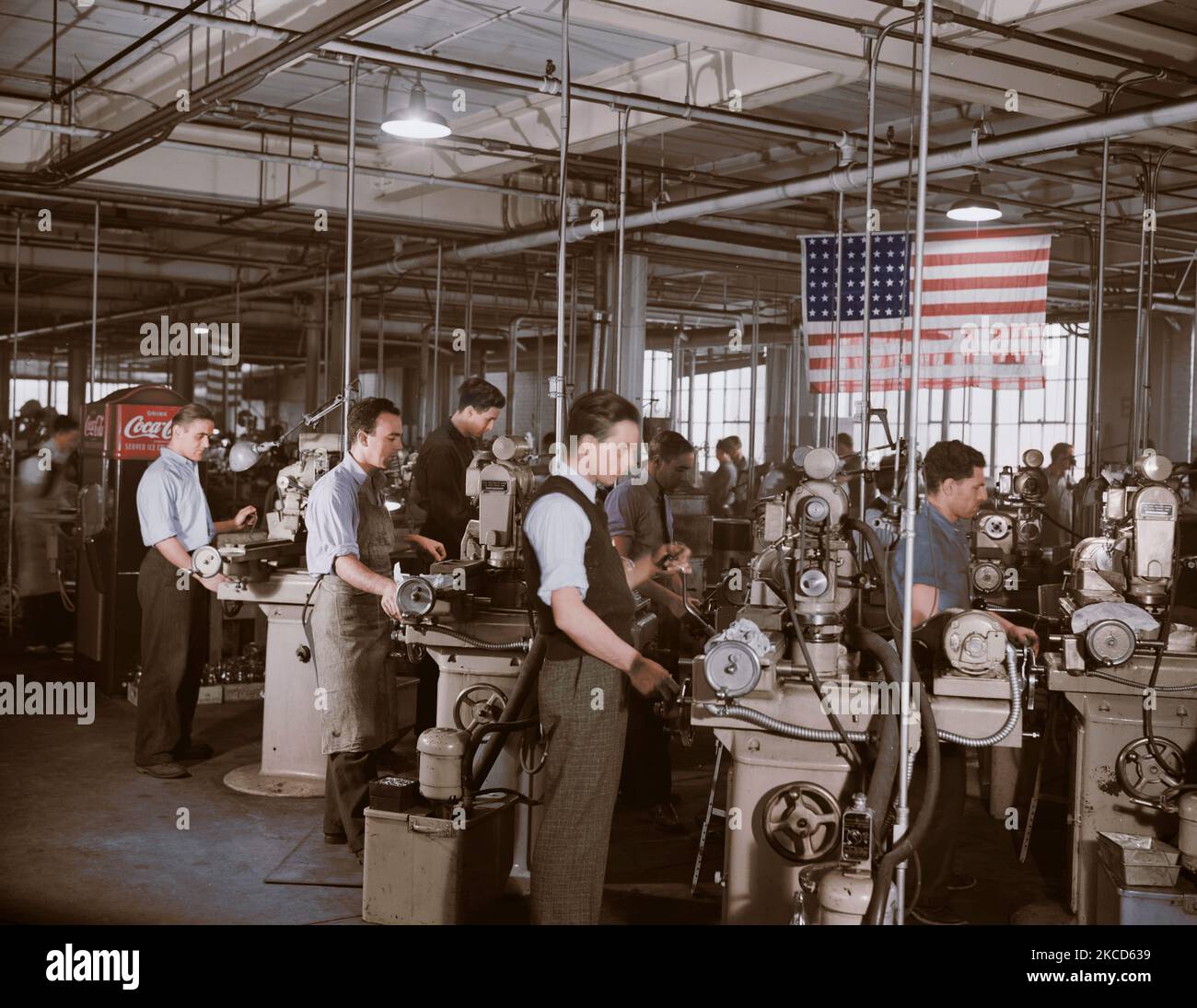Factory workers grinding small parts for machine tools to aid the war ...