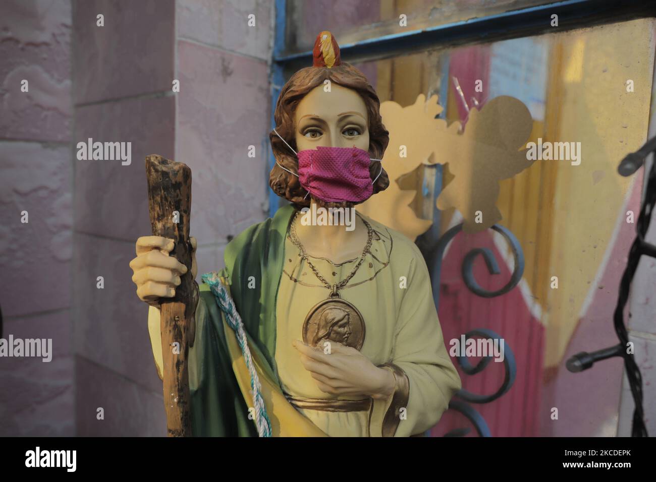 A figure of St. Jude Thaddeus with a face mask on an altar at the top ...