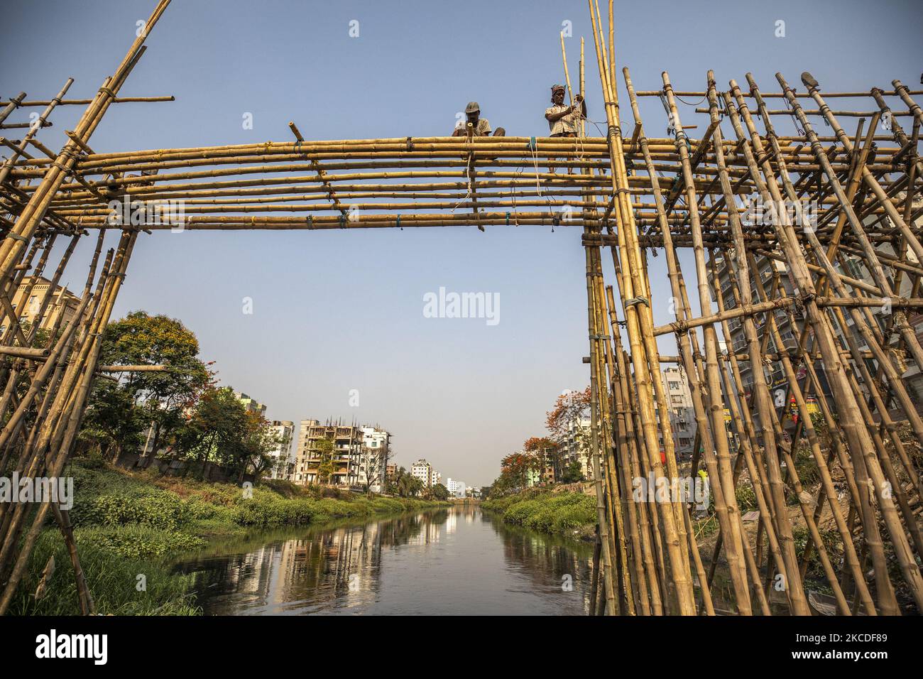 Workers repair a bamboo bridge over a polluted cannel in Dhaka ...