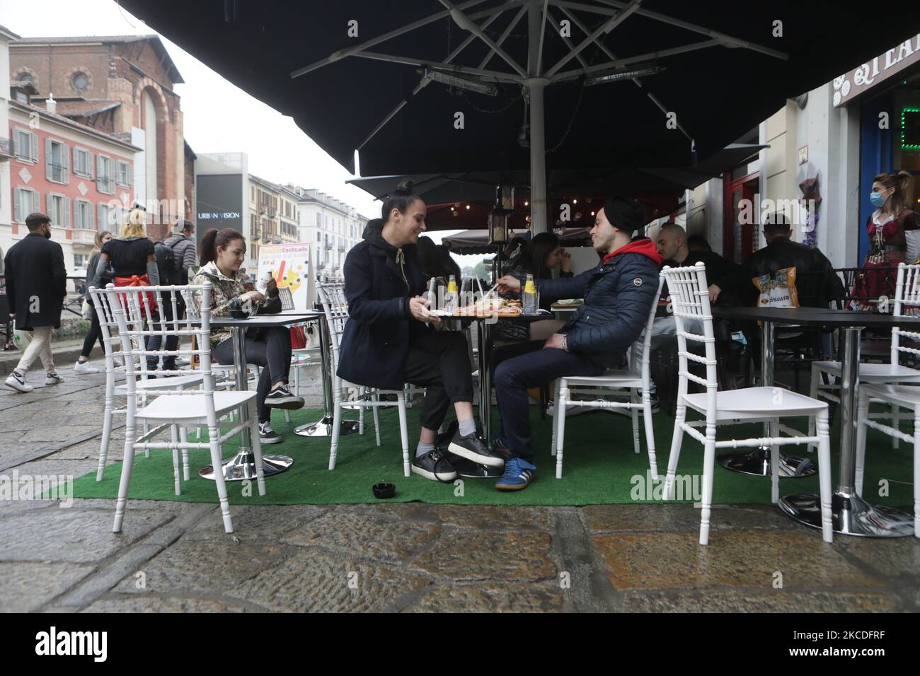 People have a drink on a bar terrace at the Navigli in downtown Milan ...