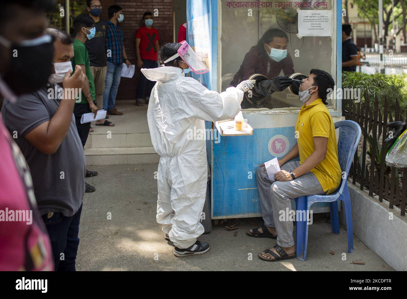 A young man is giving a sample for the covid 19 test in front of an ...
