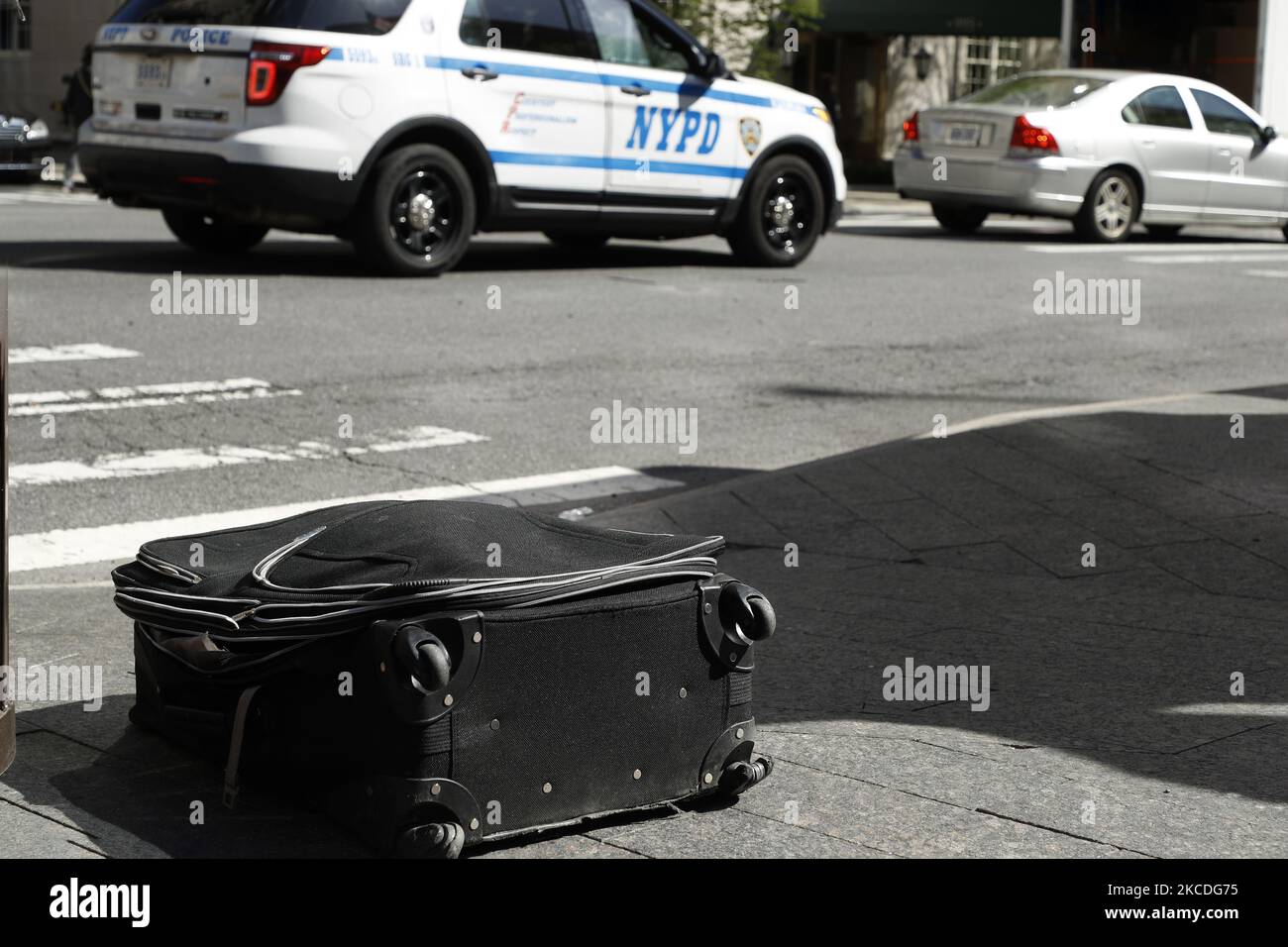 A police car drives past a suitcse after New York Police Department ...