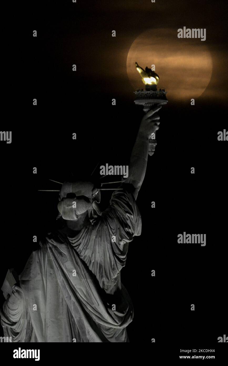 The Super Flower Moon rises behind the Statue of Liberty in New York ...
