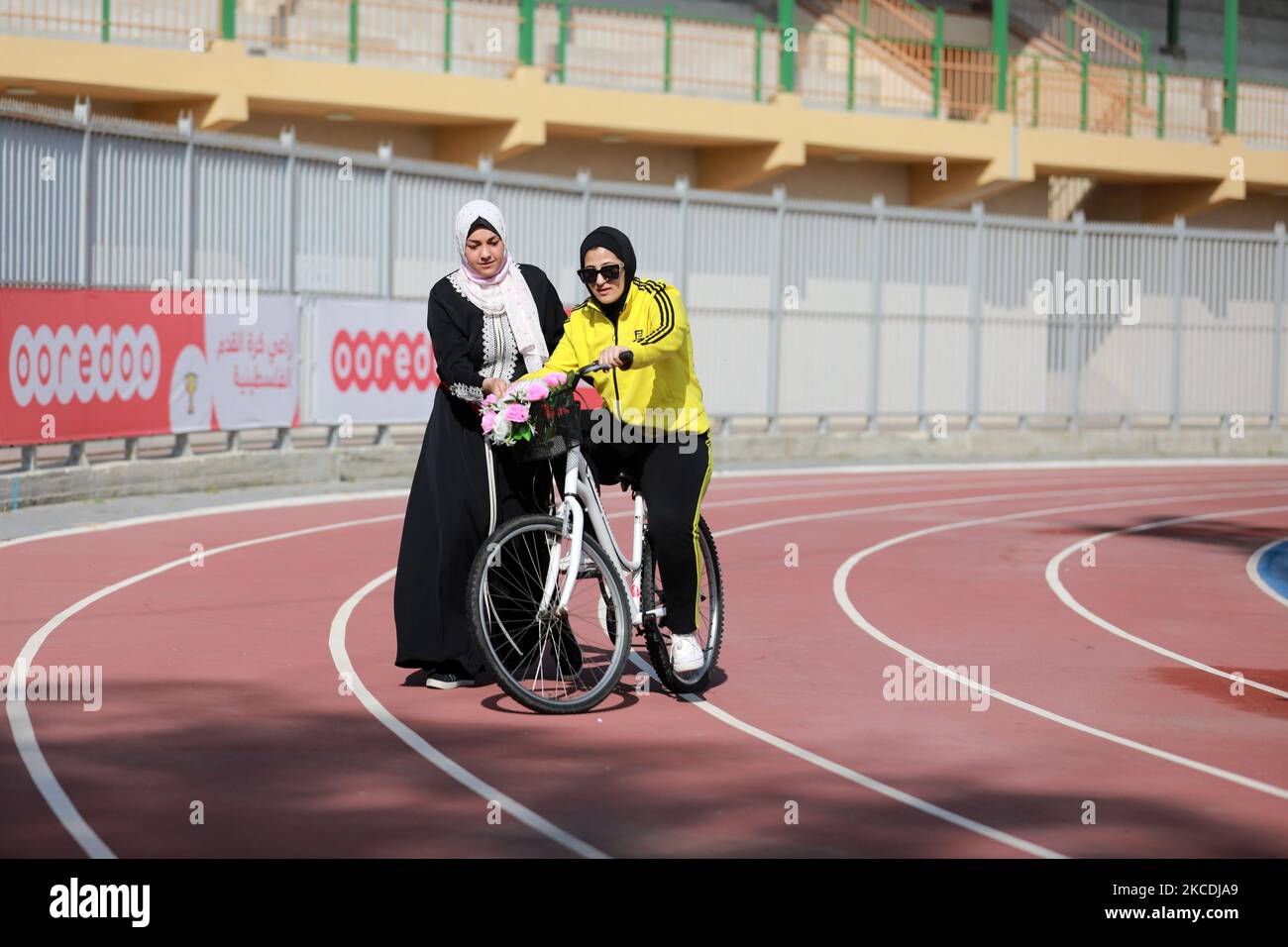 A Palestinian trainer teaches a woman how to ride a bicycle at the ...