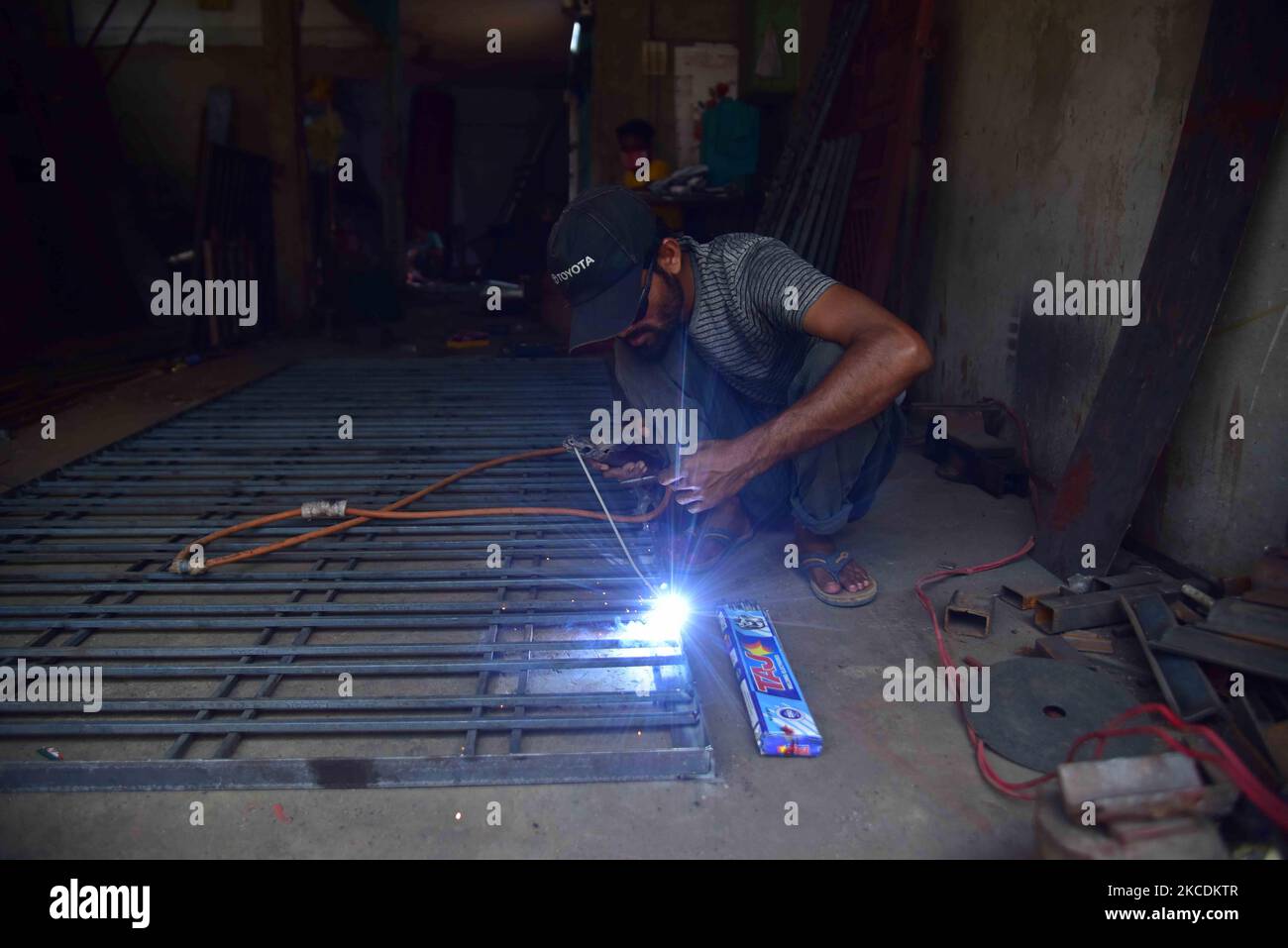 An Indian worker welds iron rods inside a workshop in Nagaon District ...
