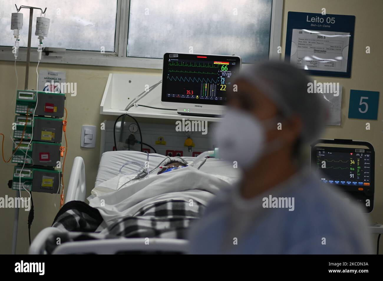 A medical worker passes in front of an intubated coronavirus disease ...
