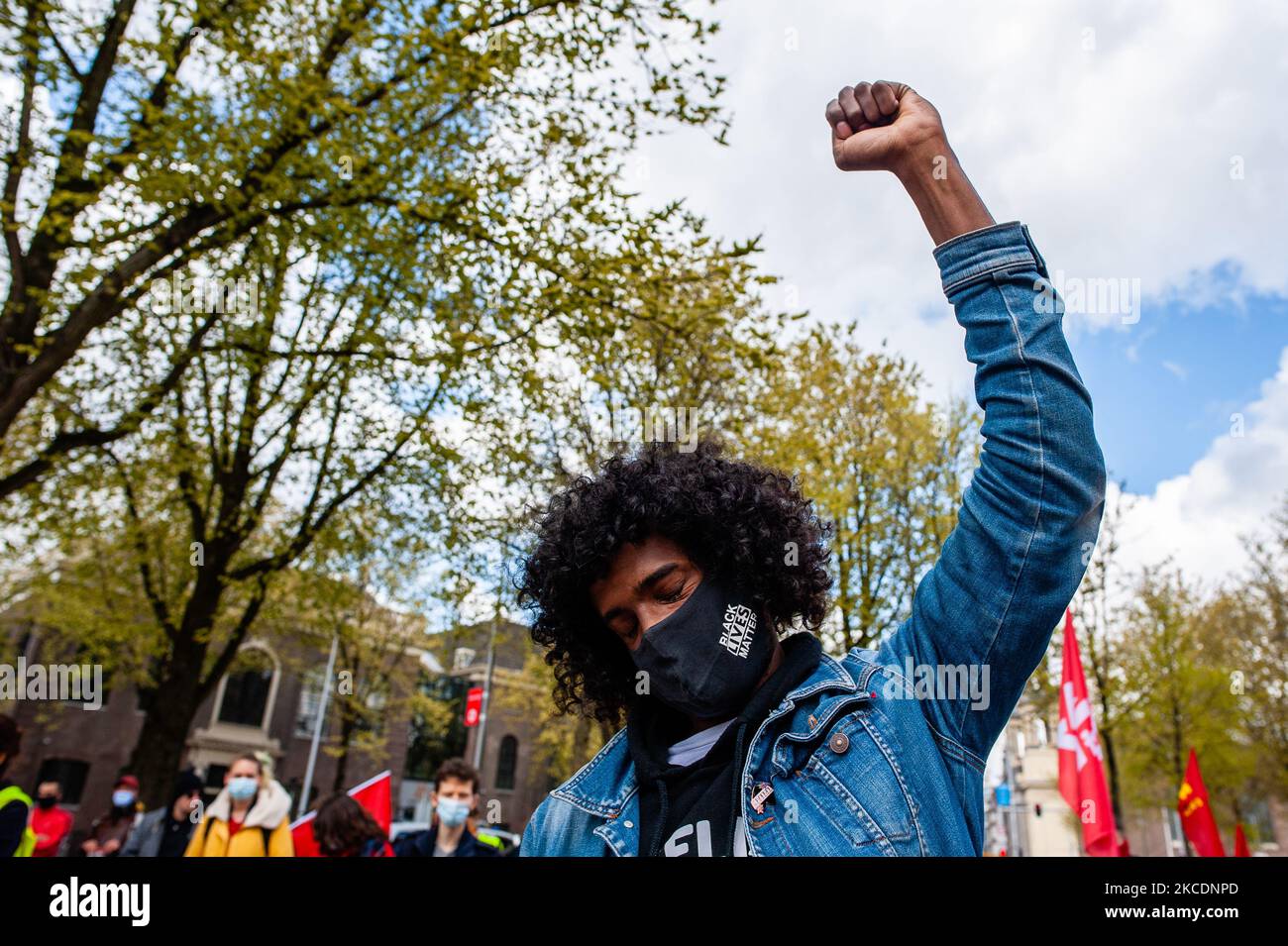 A black man is raising his hand in the sky while wearing a Black Lives ...