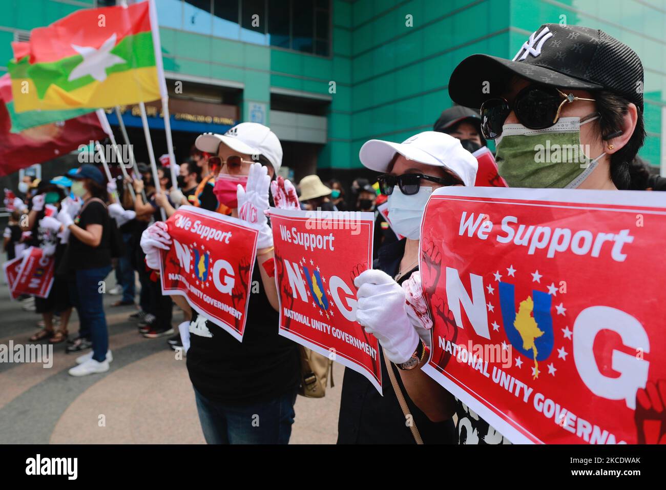 Over one thousand Burmese hold portraits of Aung San Suu Kyi, flash a three fingered salute ...