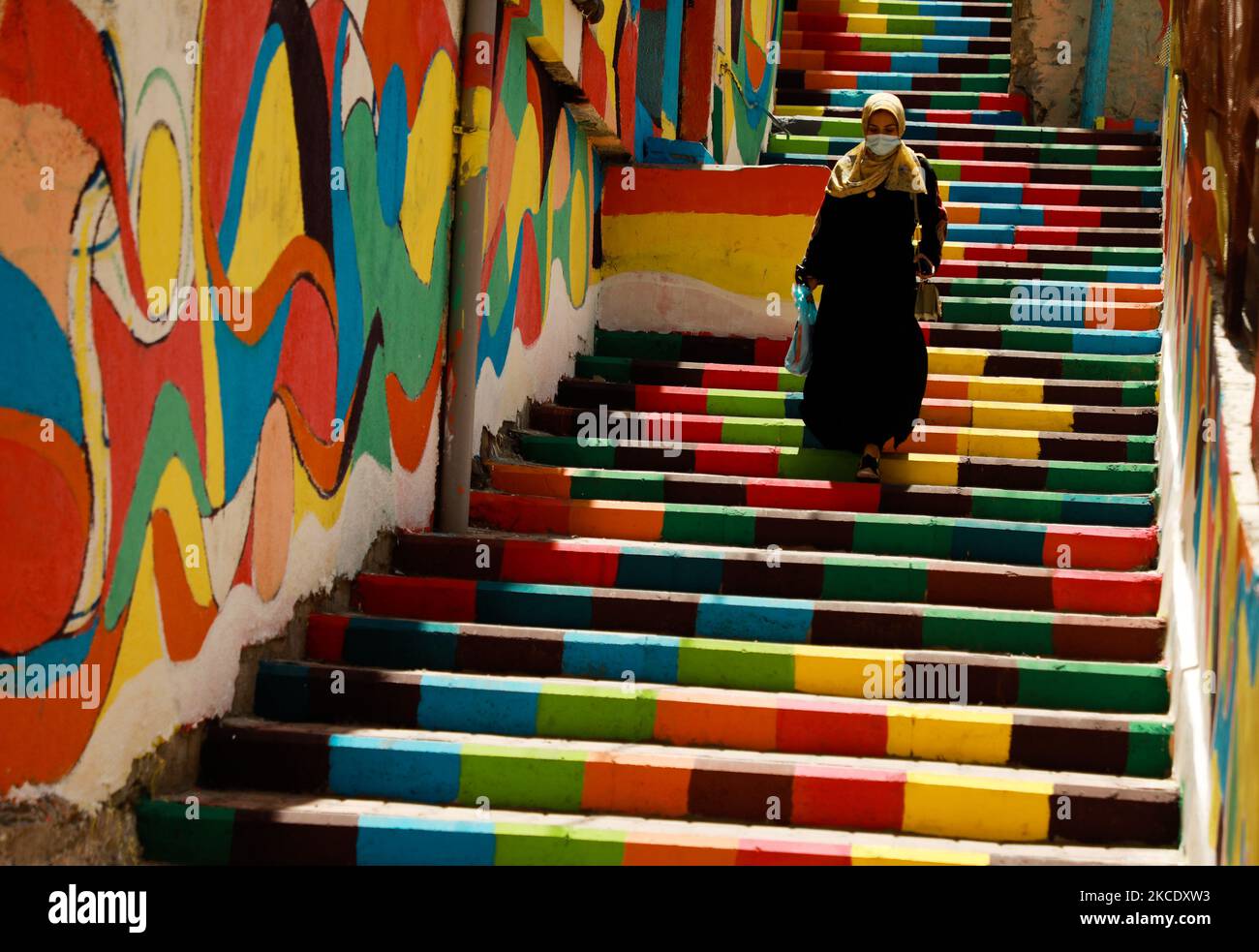 A Palestinian woman walks down steps decorated with vibrant colours in ...