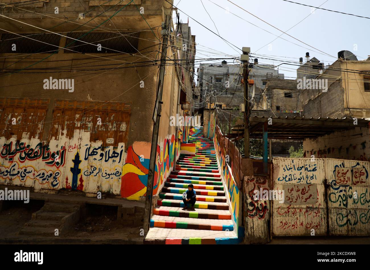 A Palestinian boy sits on steps decorated with vibrant colours in the ...