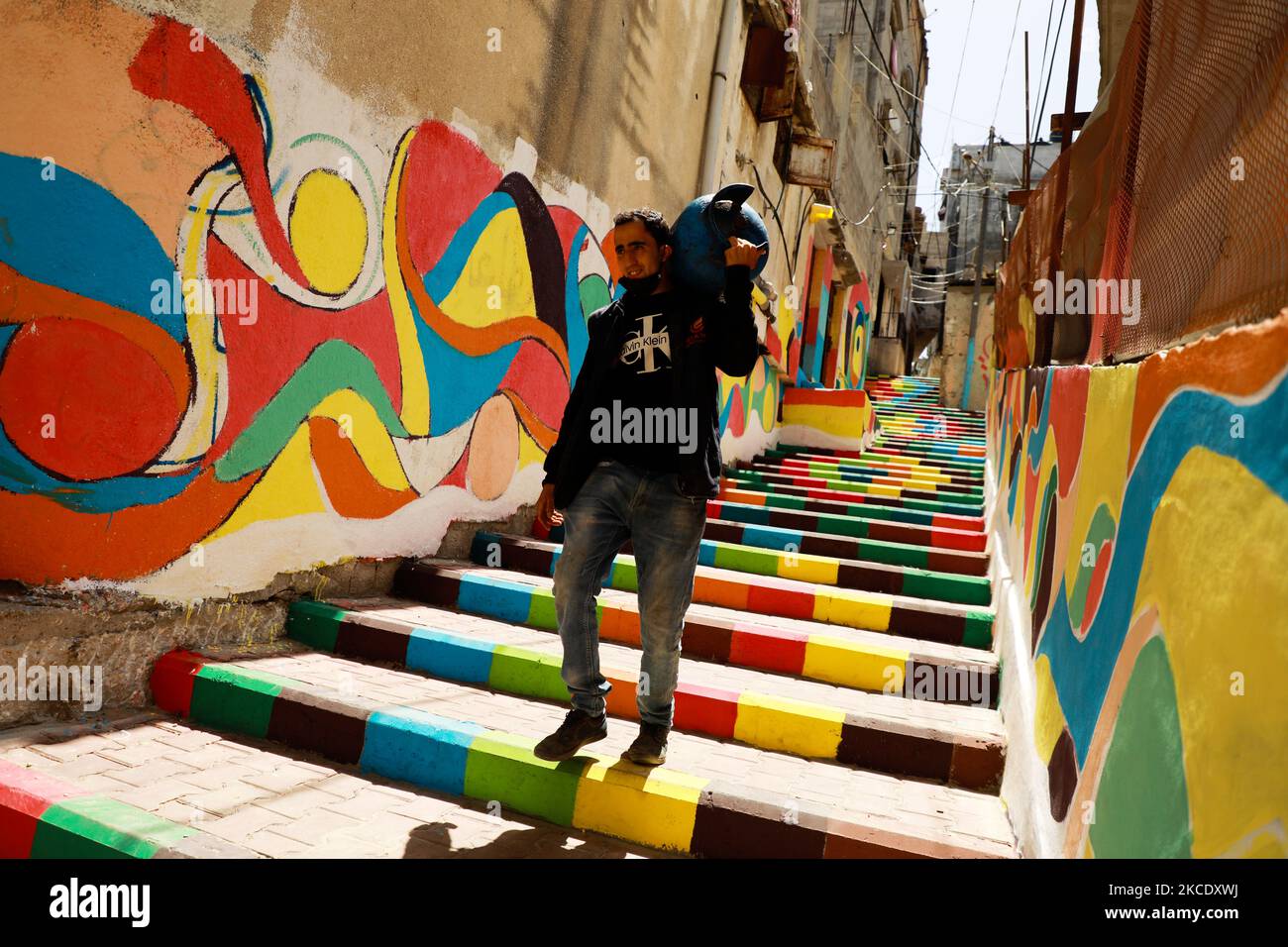 A Palestinian man walks down steps decorated with vibrant colours in ...