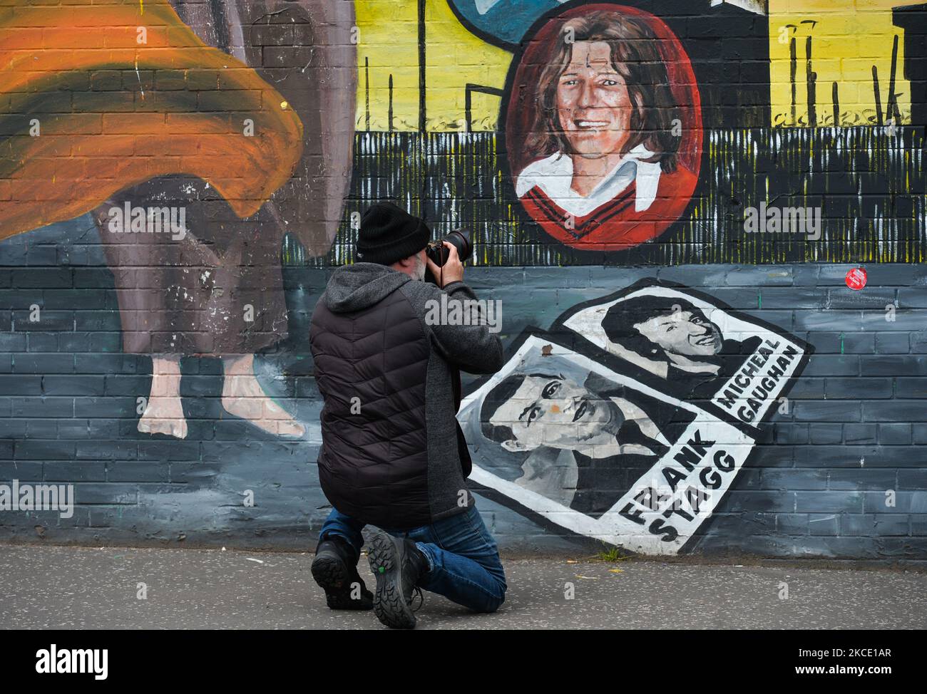 A photographer takes a picture of a memorial mural with an image of ...