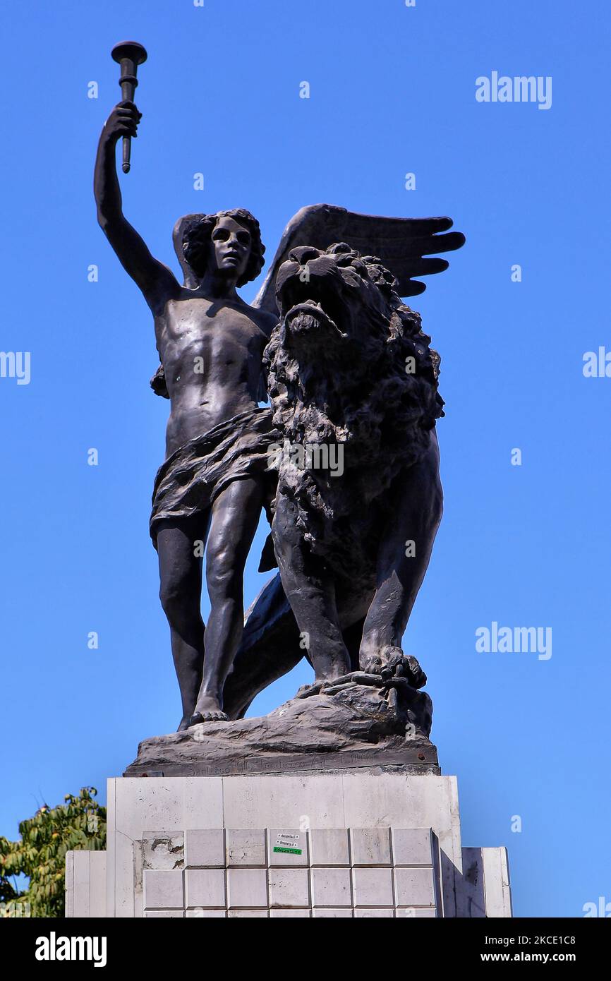 Statue of an angel holding a torch standing alongside a lion at the ...