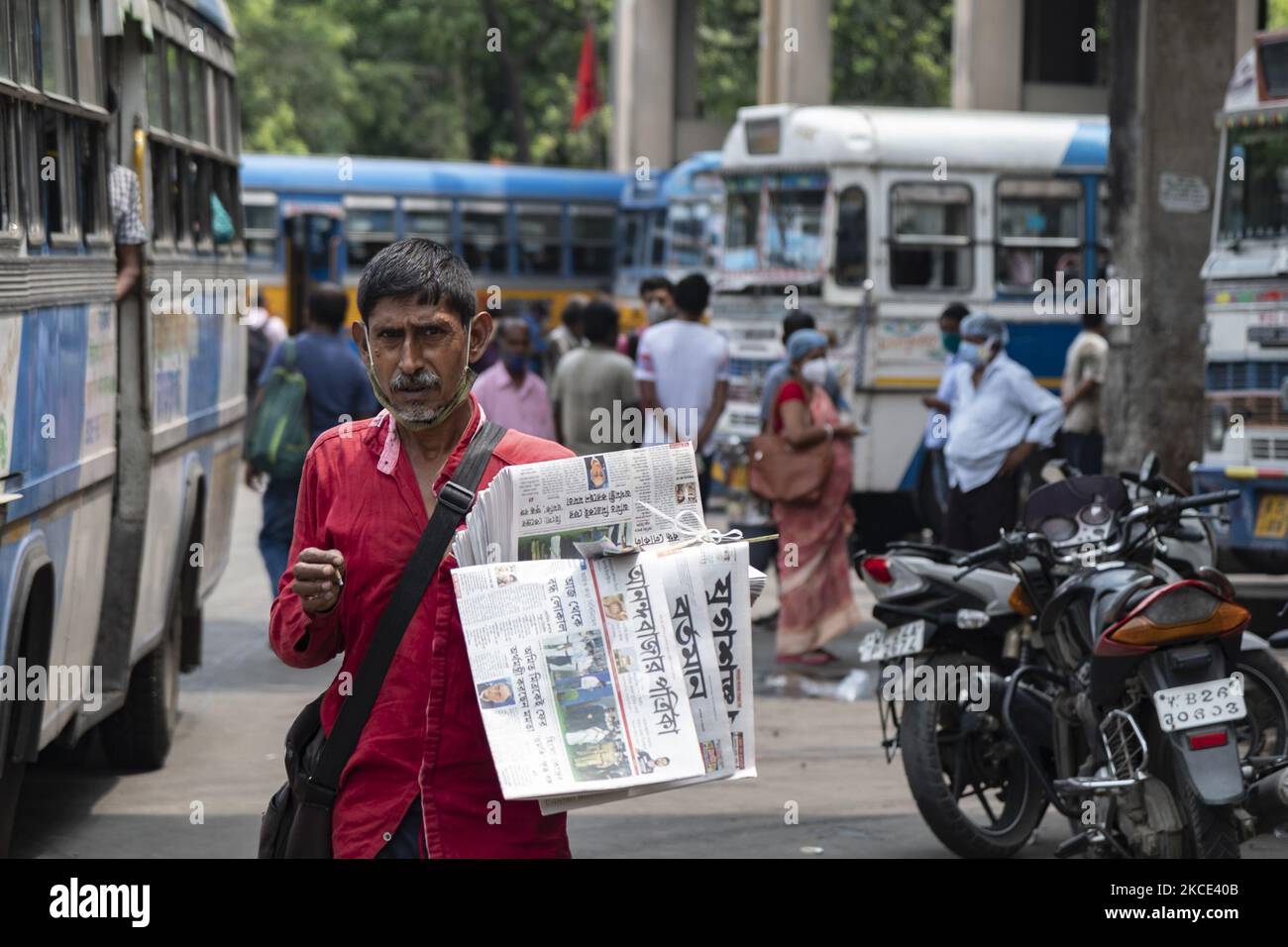 A newspaper vendor at a bus terminal without wearing a proper mask, in ...