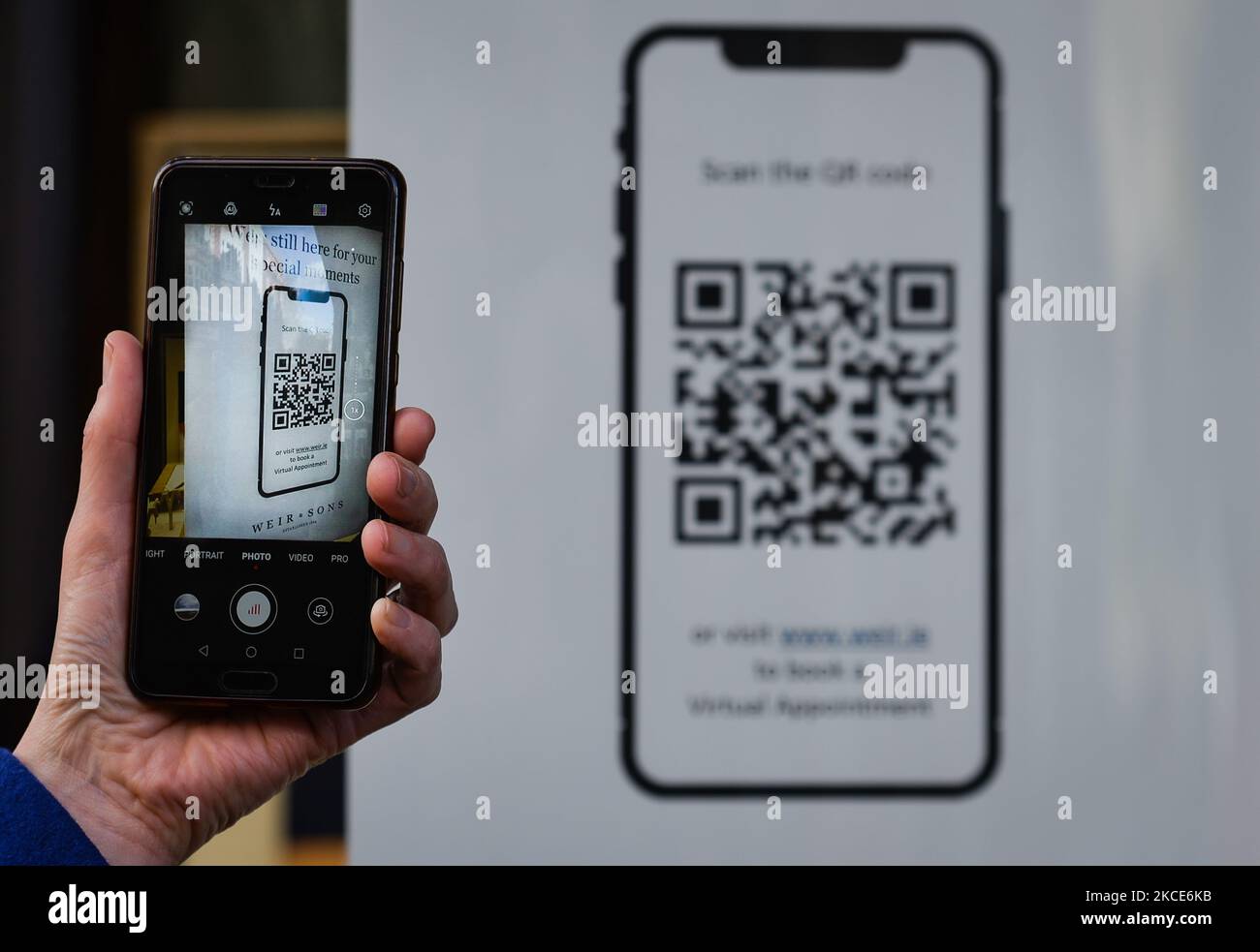 A person scans the QR code in a shop window to book a virtual ...