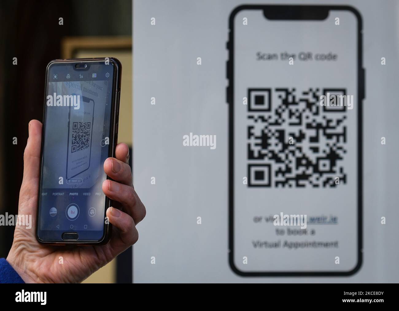 A person scans the QR code in a shop window to book a virtual ...