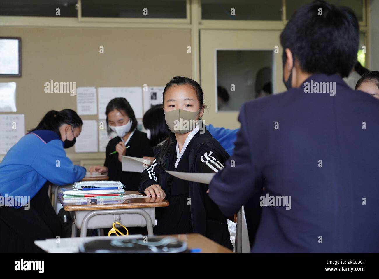 A junior high school student exchanges a handout with her classmate ...