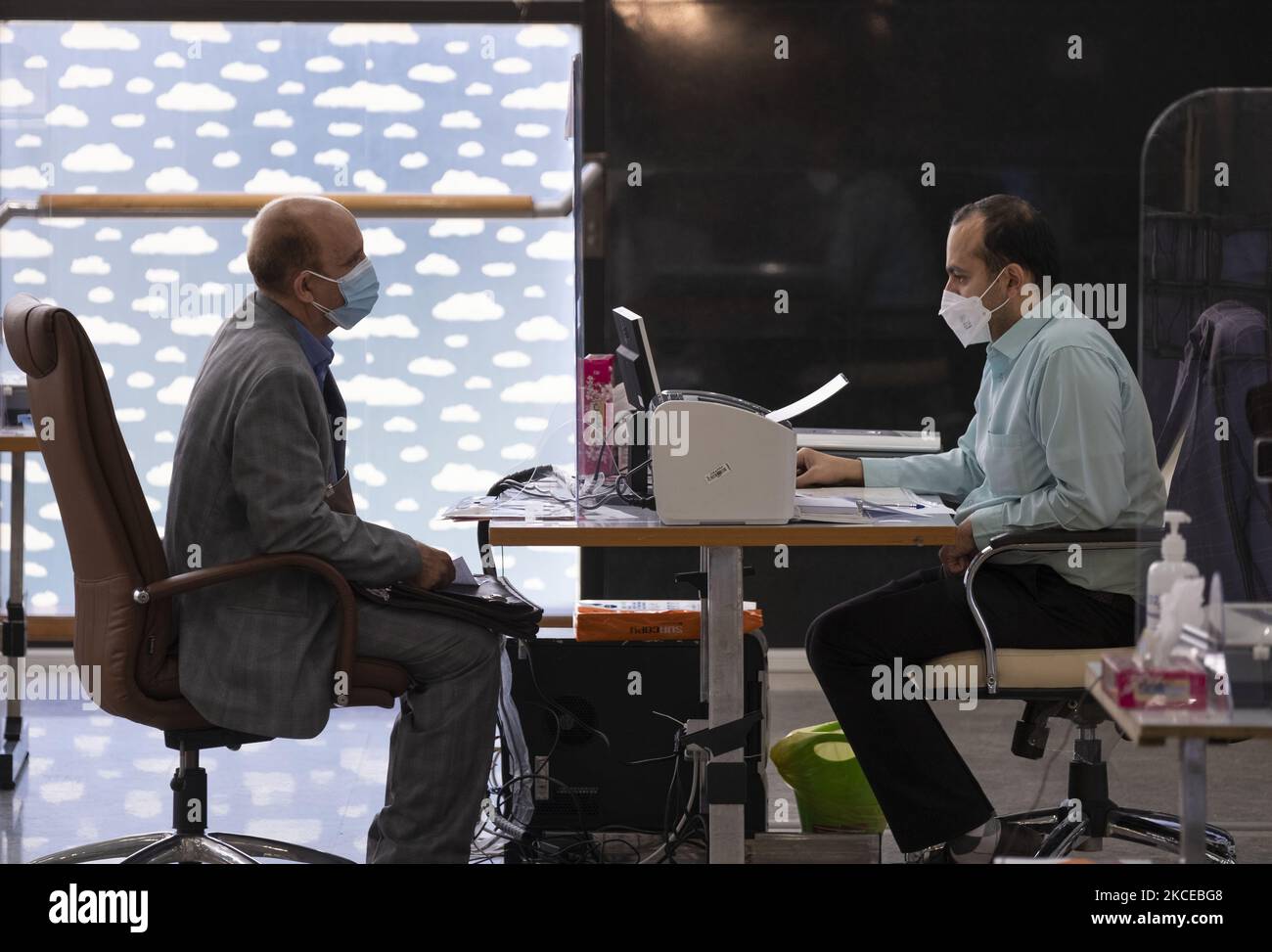 An unidentified man (L) wearing a protective face mask attends the ...