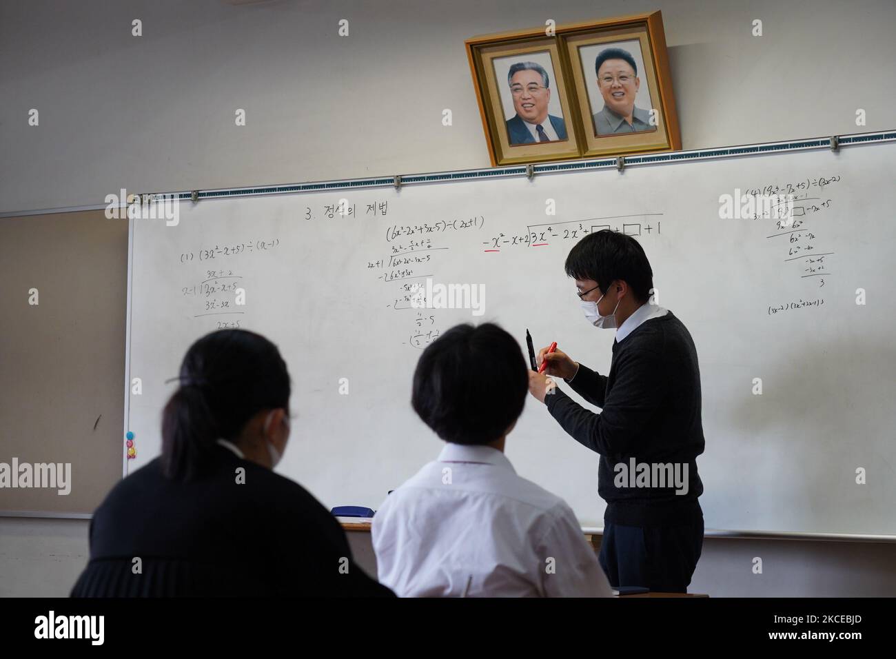 Pictures of Kim Il Sung and Kim Jong Il hang on the wall as a teacher ...