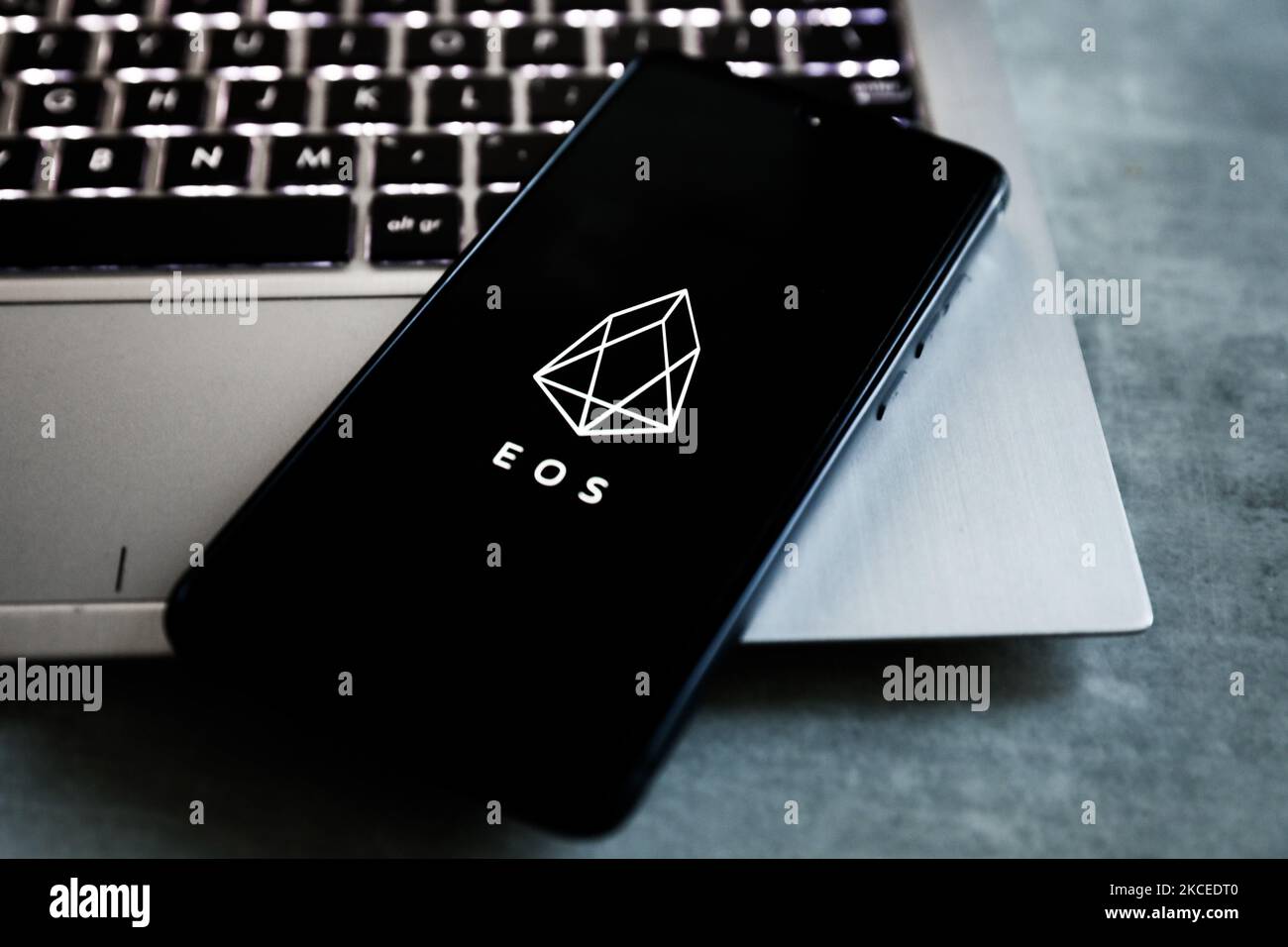 EOS cryptocurrency logo is displayed on a mobile phone screen ...