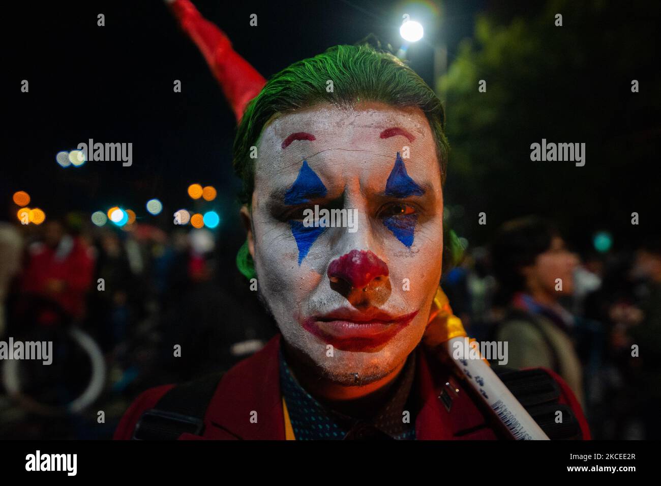 A demonstrator dressed as The Joker character poses for a portrait as ...