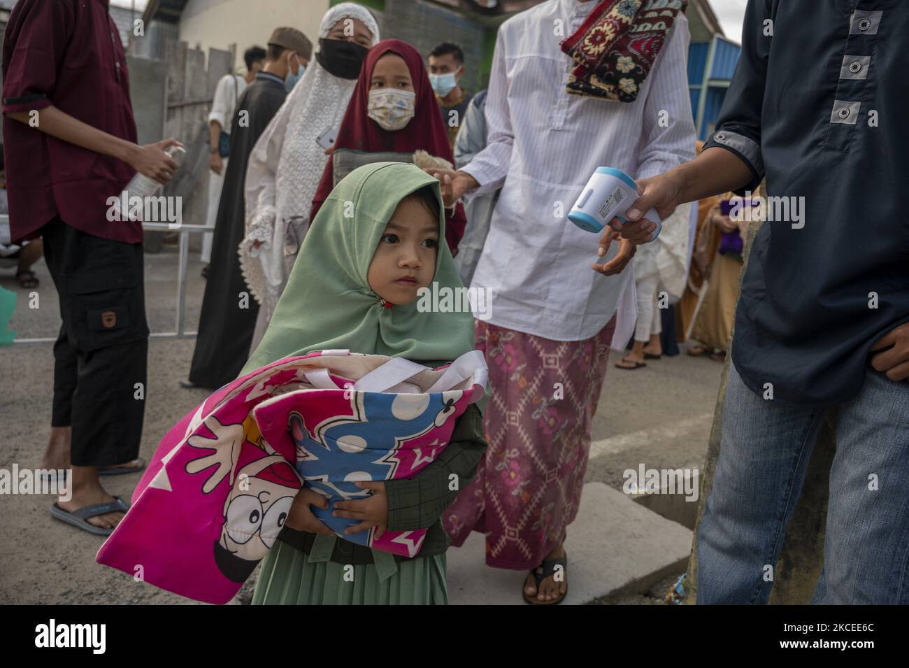 An officer checks the body temperature of a child who will participate ...